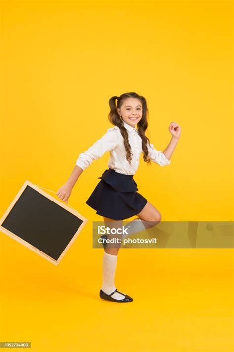 학습 모드로 돌아갑니다 노란 배경에 학교에 가는 활기찬 어린 소녀 학교 유니폼을 입은 어린 아이가 칠판을 들고 다시 수업에 학교 시간으로 돌아갑니다 다시 오신 것을