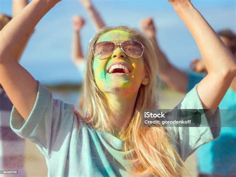 그녀의 친구와 함께 Holi 축제 축 하에서 아름 다운 금발의 여 자가 춤의 초상화 그녀의 얼굴과 옷은 화려한 분말으로 덮여 있다 배경에서 무용 하는 사람들 데이트에 대한