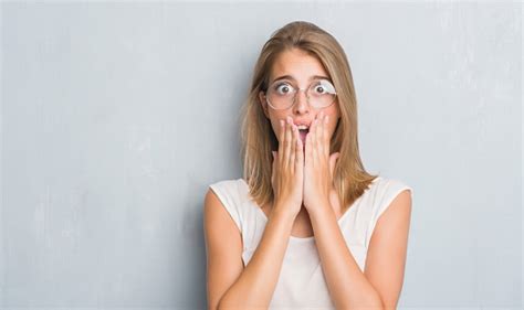 그런 지 회색 벽 입고 안경 커버 입 실수 두려움 침묵 비밀 개념에에서 무서 워의 표현에 대 한 수치와 충격 손으로 통해 서 아름 다운 젊은 여자 가리기에 대한 스톡 사진