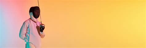 펜싱 의상을 입은 젊은 남자와 헬멧 마스크를 쓴 남자가 네온 불빛의 그라데이션 핑크옐로우 배경 위에 칼을 들고 서 있다 20 24세에 대한 스톡 사진 및 기타 이미지