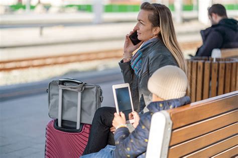 아들이 기차역에서 디지털 태블릿을 사용하는 동안 휴대전화로 이야기하는 여자 2명에 대한 스톡 사진 및 기타 이미지 2명 가족 관광객 Istock