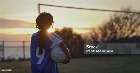 경기장에서 축구공을 든 어린 아이 일몰 청소년을 위한 활동과 피트니스가 있는 야외 스포츠 운동 건강 운동선수는 운동장에서 지평선을 바라보고 뒷모습과 운동을 한다 어린이