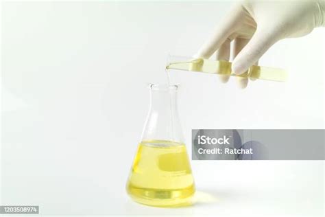 흰색 배경에 Labolatory에서 과학 유리에 유리 튜브에서 기름을 붓는 석유 테스트를 위해 석유 액체를 혼합 고무 장갑 과학자 손 개념 코커셜 윤활유 제품에 대한 연구