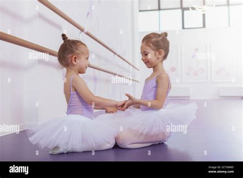 Two Adorable Little Ballerinas Holding Hands Smiling At Each Other At