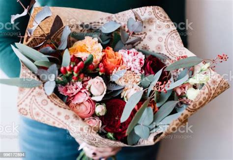 회색 벽 바탕에 파스텔 핑크와 선명한 붉은 색에 장미 핑크 라 카네이션 유 칼 리 나무의 큰 아름 다운 신선한 꽃 꽃다발을 들고 하는 아주 좋은 꽃집 여자 가까이 보기