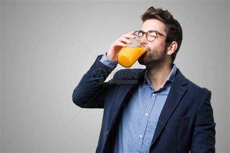 在灰色背景下喝果汁的年轻人高清图片下载 正版图片503551297 摄图网