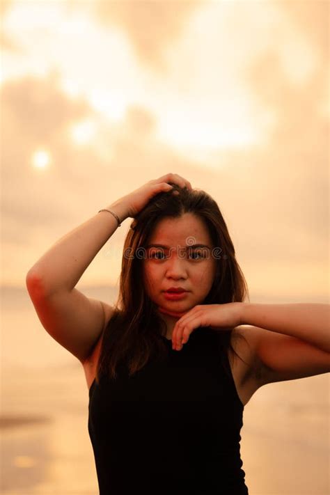 An Asian Teenager Who Is Posing By Holding Her Head And Black Hair On