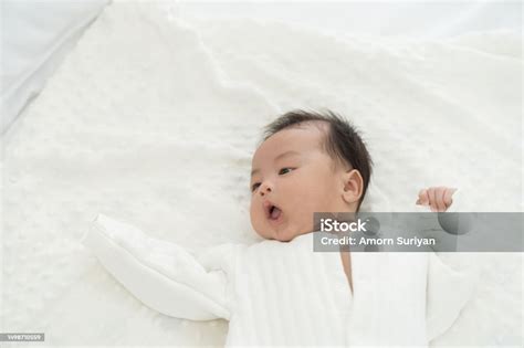 하얀 침대에 담요를 깔고 자고 있는 갓 태어난 아기의 모습 하얀 침대에 누워 있는 아기 아시아 신생아가 자고 있다 아시아 유아