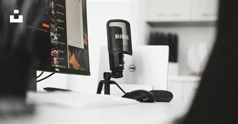 컴퓨터 모니터 옆에 있는 검은색 Rode 콘덴서 마이크 사진 Unsplash의 무료 스튜디오 이미지