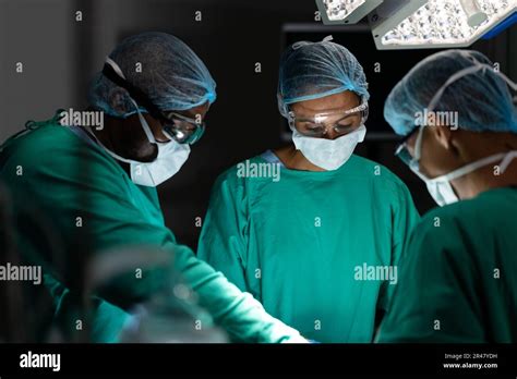 Diverse Male And Female Surgeons Operating On Patient In Operating Theatre At Hospital Stock
