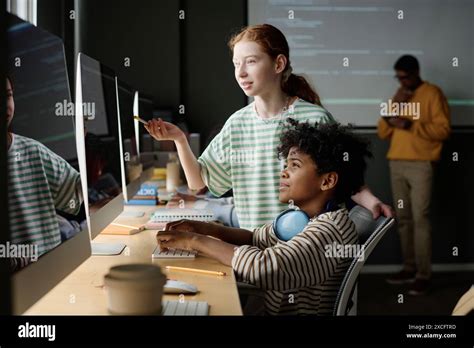 Caucasian Teen Girl Helping Her African American Male Classmate During Computer Coding Class At