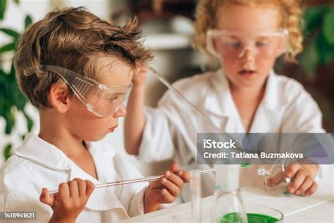 실험실에서 화학 실험을 수행하는 흰색 유니폼을 입은 진지한 어린 소년과 소녀 학교 개념으로 돌아 가기 젊은 과학자 자연과학 유치원 및 아동의 학교 교육 2명에 대한 스톡
