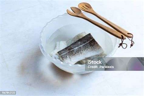 소금에 절인 말린 대구 물고기 는 물을 가득 플라스틱 그릇에 탈염하고 요리하고 흰색 배경에 나무 숟가락 건강하고 맛있는 음식 대구 바닷물고기에 대한 스톡 사진 및 기타