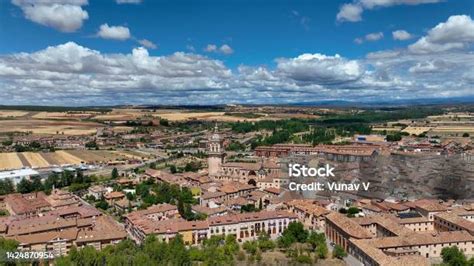화창한 여름날 스페인의 주거용 건물의 갈색 타일 지붕에 대한 높은 고딕 양식의 종탑이있는 중세 로마 카톨릭 대성당의 아름다운