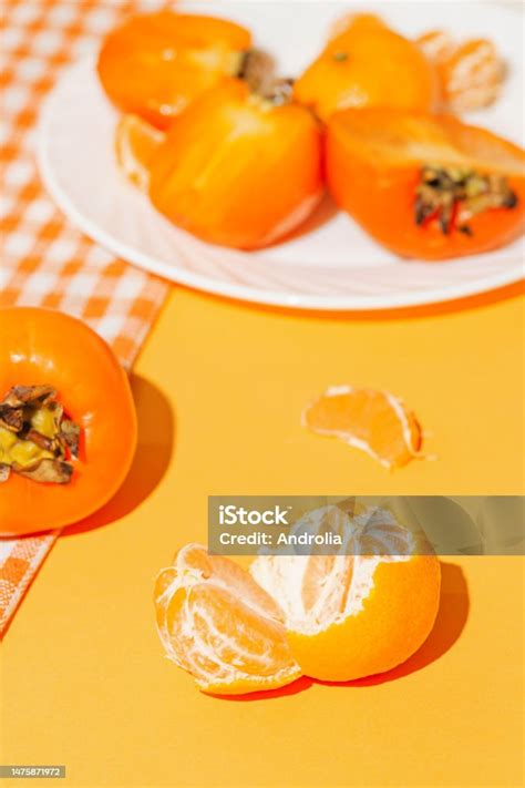 주황색 만다린으로 만든 창의적인 레이아웃 그림자가 있는 밝은 배경에 흰색 접시에 신선한 감 과일 건강 한 음식 개념입니다 여름 피크닉 아이디어 소풍 음식에 대한 스톡 사진