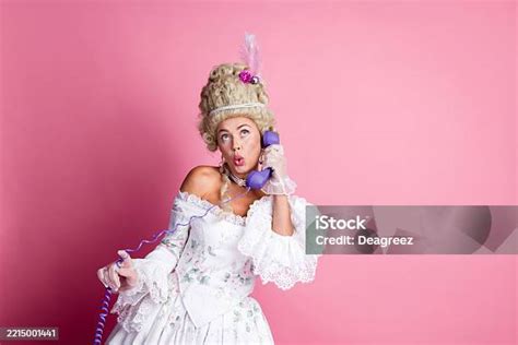 바로크 양식의 가운을 입은 우아한 귀족 여성이 전화를 들고 분홍색 배경에 유머러스한 표정으로 포즈를 취하고 있습니다 40 44세에 대한 스톡 사진 및 기타 이미지 Istock