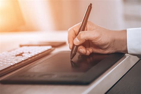 그래픽 디자이너의 작업 영역입니다 펜 태블릿에 손 똑똑한 젊은이 사무실에서 무료 검은 모니터 복사 공간 디자인에 대 한입니다 태양 빛의 따뜻한 섬광 개념에 대한 스톡 사진