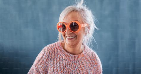 괴상한 선글라스를 낀 고위 여성의 초상화는 어두운 배경을 배경으로 실내에 서서 웃고 있다 사진 Unsplash의 슬로바키아 이미지