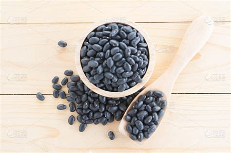 木杯上的黑豆放在麻袋背景上