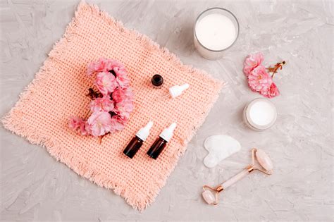 회색 콘크리트 배경에 에센셜 오일 크림 항아리 페이스 롤러 괄사 돌 분홍색 벚꽃이 있는 갈색 유리병 피부 관리 미용 치료 개념 평면도 플랫 레이 건강한 생활방식에 대한 스톡