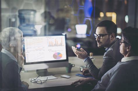 어두운 사무실에서 데스크톱 Pc에서 작업 하는 동안 차트에 대해 얘기 하는 비즈니스 동료 사업가에 대한 스톡 사진 및 기타 이미지 사업가 컴퓨터 컴퓨터 모니터