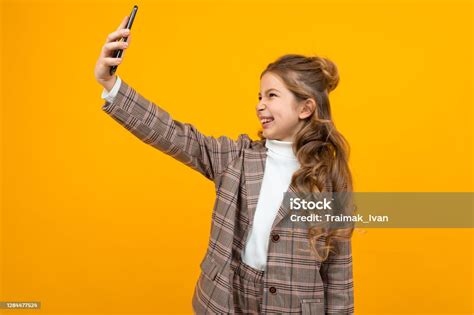 고전적인 재킷에 웃는 세련된 금발의 백인 소녀는 노란색 스튜디오 배경에 스마트 폰에 사진을 찍습니다 10 11세에 대한 스톡 사진 및 기타 이미지 Istock