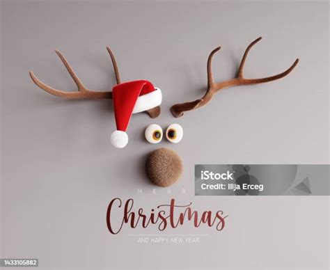 กวางเรนเดียร์ตลกกับหมวกซานต้าและข้อความสุขสันต์วันคริสต์มาสบนพื้นหลังสีเทา ภาพสต็อก ดาวน์โหลด
