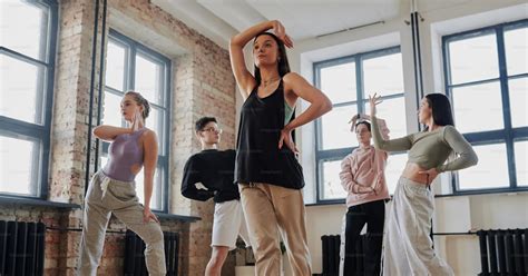 팔을 머리 위로 올린 젊은 여성 연기자가 댄스 그룹 앞에 서서 유행 춤의 새로운 동작을 배우고 있다 사진 Unsplash의 춤 이미지