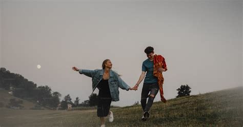 시골의 해질녘에 자연 속에서 걷고 손을 잡고 달리는 젊은 부부의 정면 사진 Unsplash의 손을 잡고 이미지