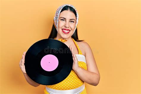 Young Hispanic Woman Wearing Pin Up Style Holding Vinyl Disc Smiling