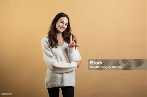 흰색 스웨터에 젊은 아름다운 여자의 이미지는 오렌지 벽 배경에 고립 포즈와 보여주는 2 손가락 20 29세에 대한 스톡 사진 및 기타 이미지 Istock