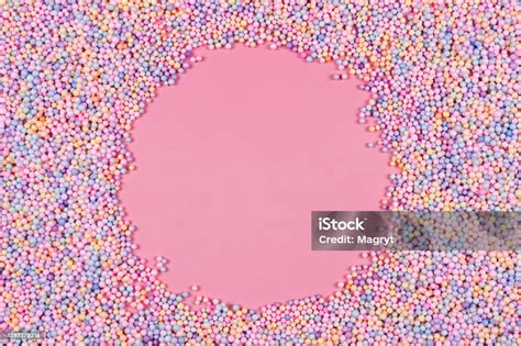 분홍색에 파스텔 컬러 볼로 만든 둥근 프레임 스티로폼 또는 폴리스티렌 폼 배경 과자 장식을위한 다채로운 설탕 공의 혼합 무지개 색 설탕 칩 드래그 스핀 과자 구에 대한 스톡