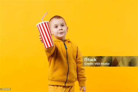작은 재미 쾌활 한 아이 소년 34 년 된 노란색 옷 입고 오렌지 벽 배경 어린이 스튜디오 초상화에 고립 된 소 다 컵 개최