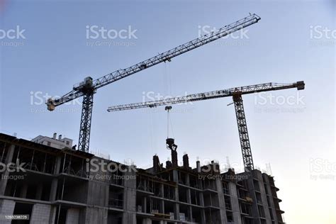 일몰 배경에 건설 현장에서 새로운 주거 건물을 건설 타워 크레인의 실루엣 크레인은 콘크리트 양동이를 들어 올리는 것입니다 양식에 대한 시멘트 믹스를 붓는 빌더 소프트 포커스