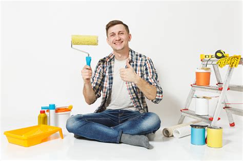 페인트 롤러 악기 재건축 아파트 방 바닥에 앉아 캐주얼 옷에서 남자 흰색 배경에 고립 벽지 액세서리를 붙이기 그림 도구 수리 가정 개념입니다 개선에 대한 스톡 사진 및 기타