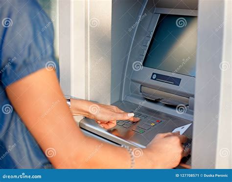 Woman Using Atm Holding Card And Pressing The Pin Security Number On