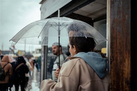 우산을 쓰고 비 속에서 길을 건너는 여성 · 무료 스톡 사진