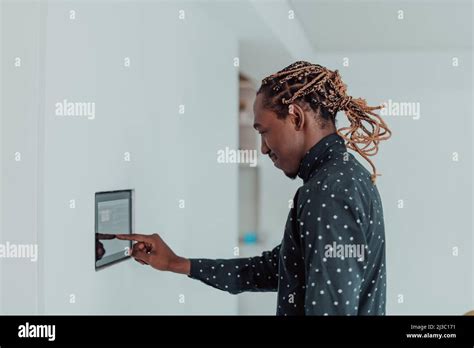smiling african american man using modern smart home system controller