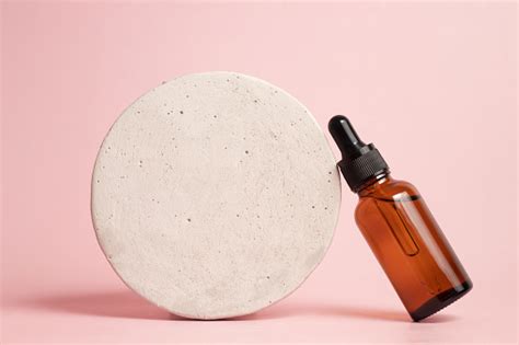 유리 드롭퍼 병 분홍색 배경에 돌 연단 스킨케어 제품 천연 화장품 얼굴과 바디 케어를 위한 뷰티 컨셉 강단에 대한 스톡 사진 및