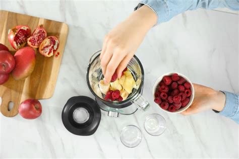 Woman Adding Raspberry Into Blender With Ingredients For Smoothie At