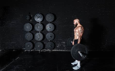 젊은 땀이 강한 근육 적합 남자 무거운 바벨 무게를 들고 하드 코어 크로스 역도 또는 데드 리프트 운동 훈련을 시작 하는 체육관