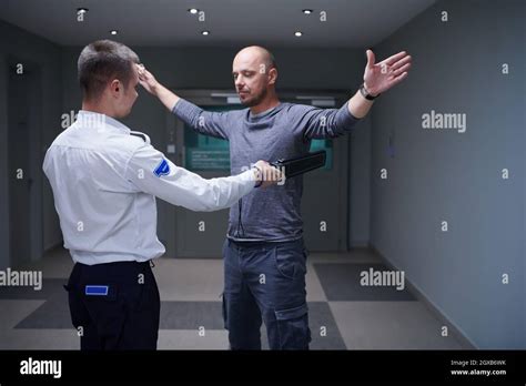 Security Guard Making Body Searching Procedure With A Metal Detector On