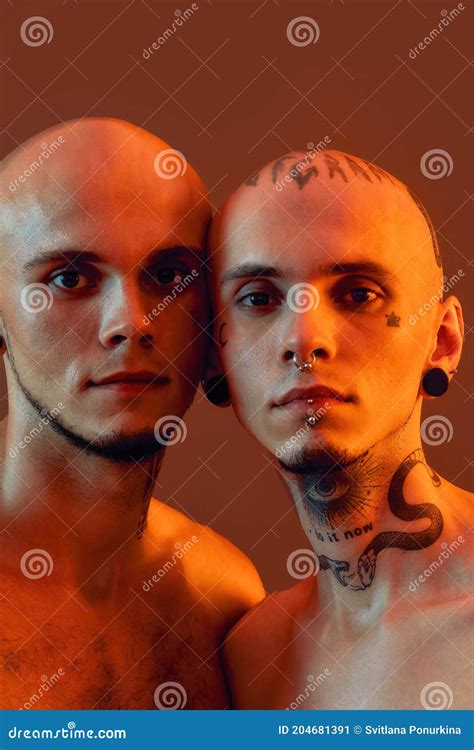 Close Up Portrait Of Young Half Naked Twin Brothers With Tattoos And Piercings Looking At Camera