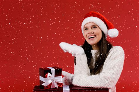 빨간 산타 모자와 흰색 장갑에 행복한 젊은 흥분 여자는 빨간색 배경에 고립 된 눈송이를 불고 25 29세에 대한 스톡 사진 및 기타 이미지 Istock