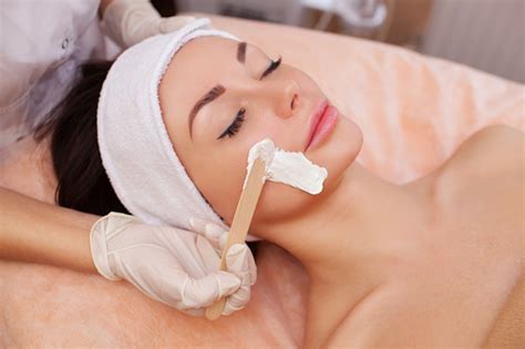 젊은 여자의 얼굴에 막대기로 마스크를 적용 하는 클렌징과 피부 보습의 절차에 대 한 미용사 가꿔주기에 대한 스톡 사진 및 기타 이미지 가꿔주기 건강관리와 의술 건강한