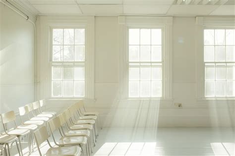 A Row Of White Chairs Neatly Arranged In A Softly Lit Classroom A Serene Classroom Bathed In