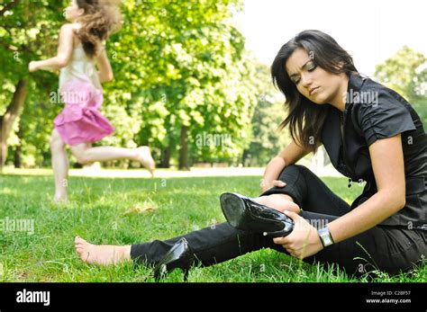 One Woman Running Barefoot In Park And Second Is Taking Her Shoes Off