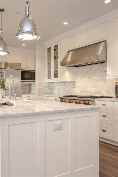 White Kitchen With Marble Counter Tops And Pendant Lights White