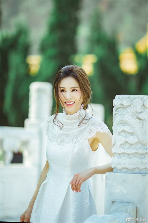 李若彤一袭白裙漫游宫廷 手持鲜花低头阅读娇媚动人娱乐环球网