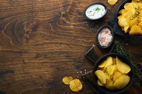 감자칩 패스트 푸드 파삭 파삭 한 감자 칩은 오래된 부엌 테이블 나무 배경에 나무 스탠드에 사워 크림 소스와 양파와 함께 세라믹